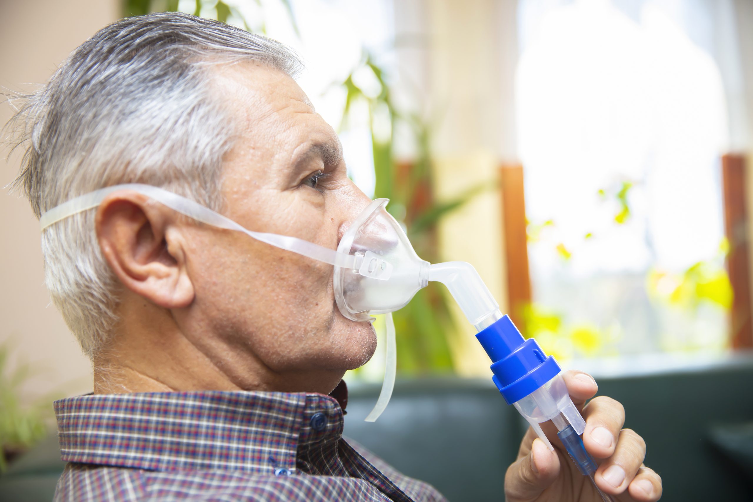Senior man using medical equipment for inhalation with respirato | Biocase